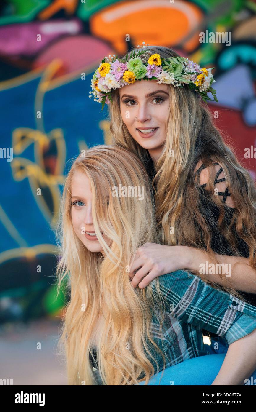 Two young women with long blonde hair smile and have fun in a vibrant ...