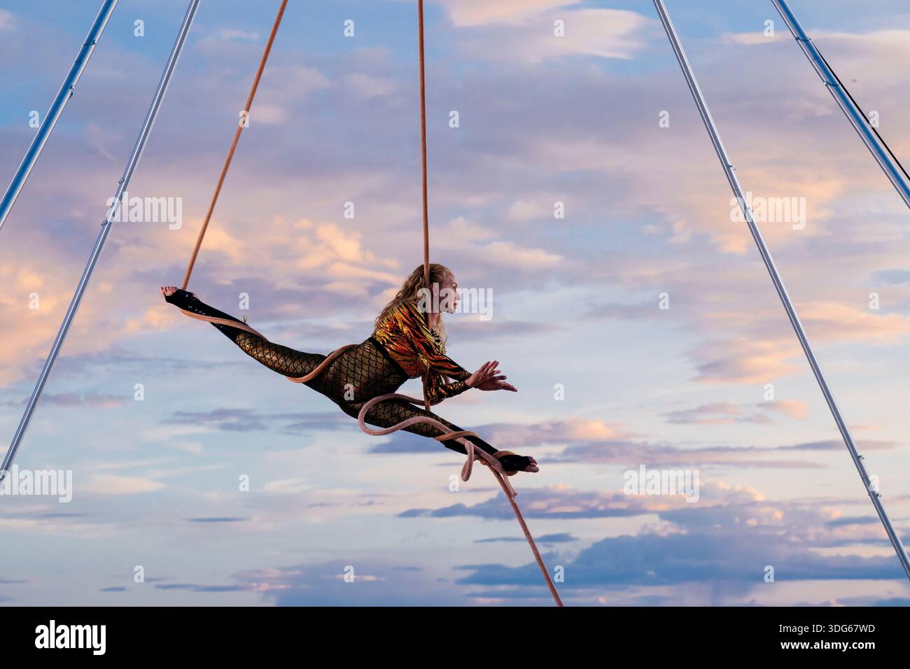 Aerial performer gracefully balances in a split pose against a vibrant ...