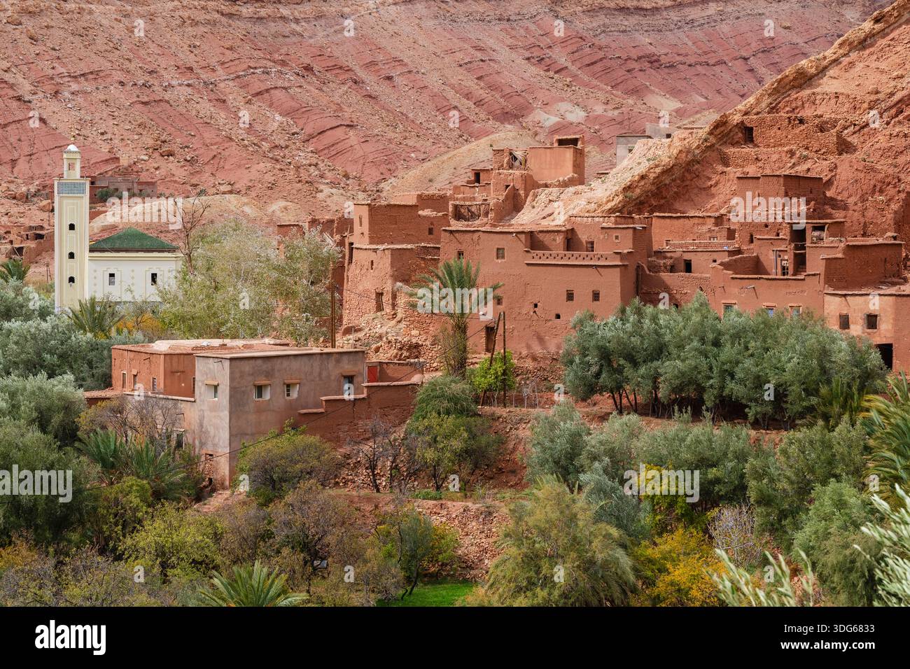 Traditional adobe buildings and a mosque amidst lush greenery and red ...