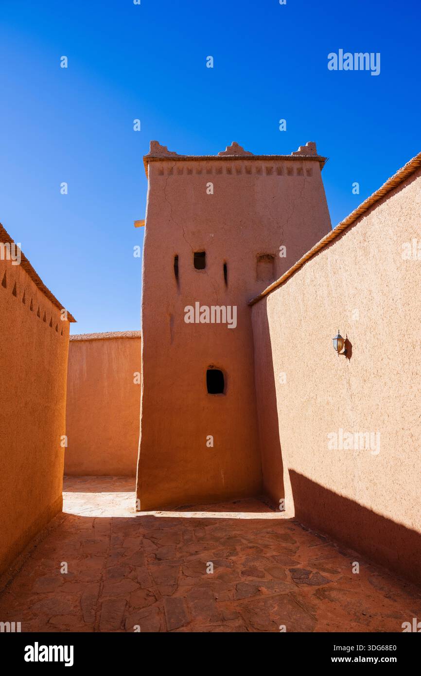 Sunlit adobe structure with narrow pathways and vivid blue sky backdrop ...