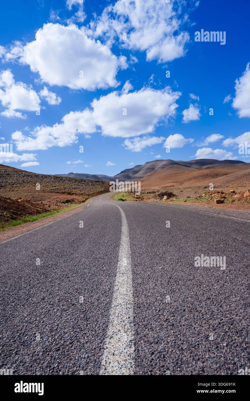 Empty winding road through rocky landscape under a clear blue sky with ...