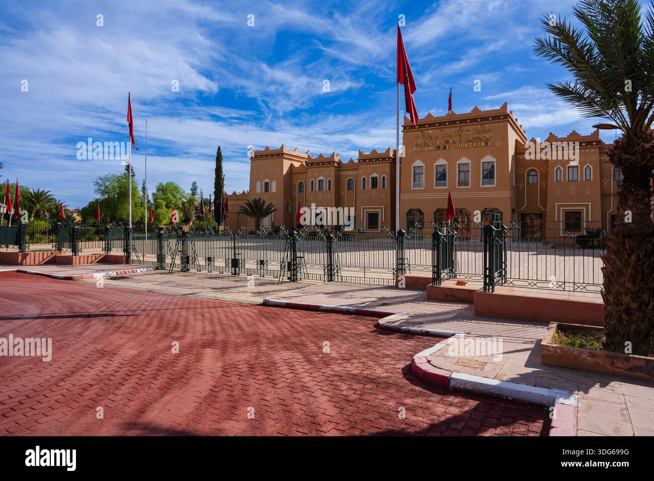Ornate building with flags, palm trees, and blue sky in a sunny outdoor ...