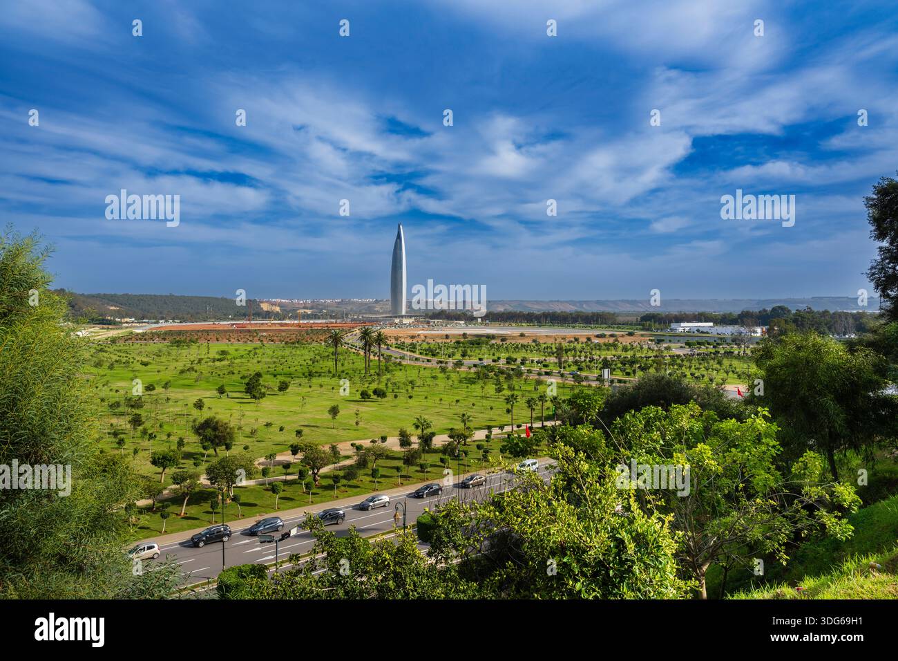 A tall modern tower overlooks a vast green landscape with trees and a ...