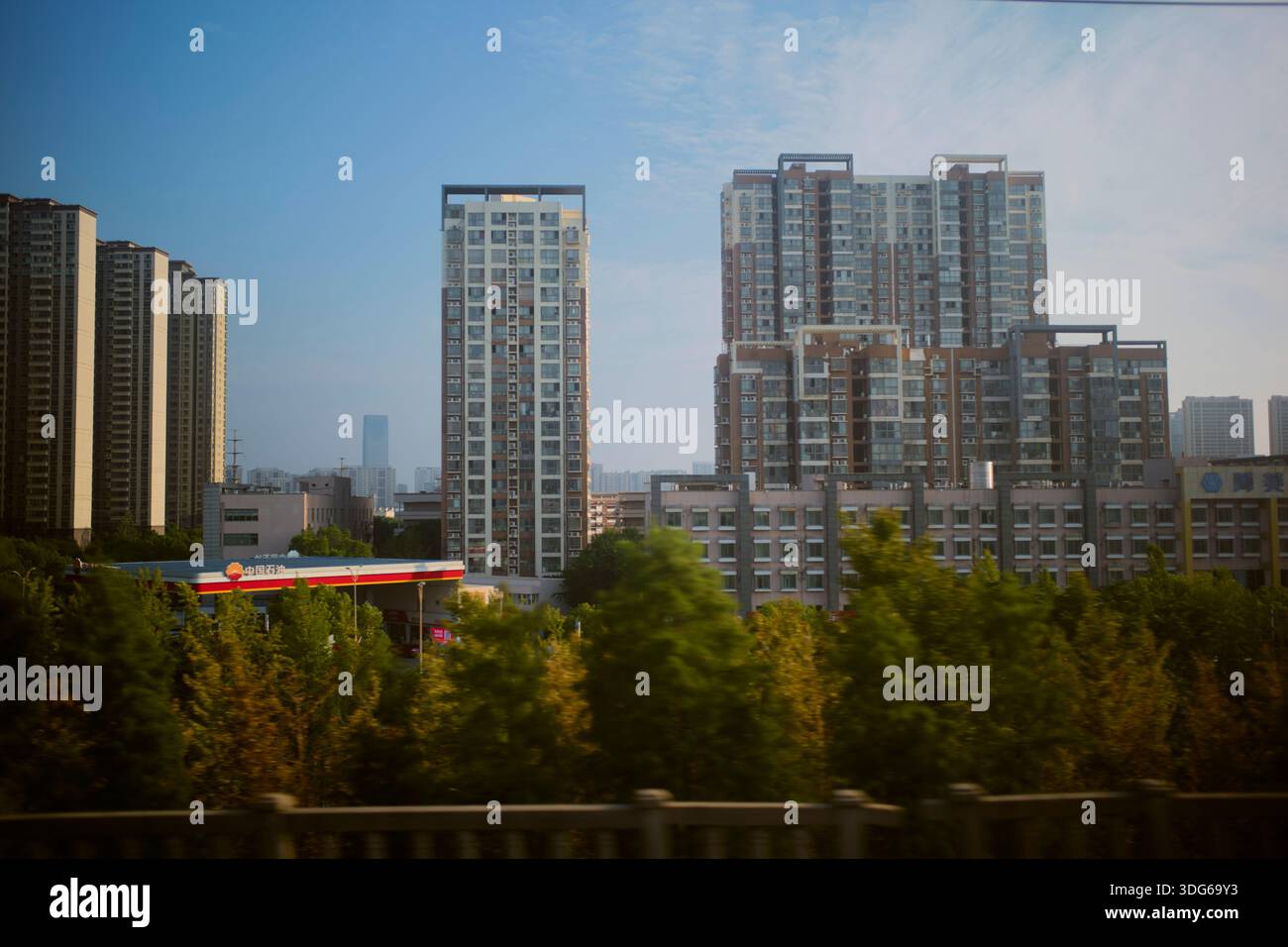 Urban skyline with tall modern buildings and lush green trees below ...