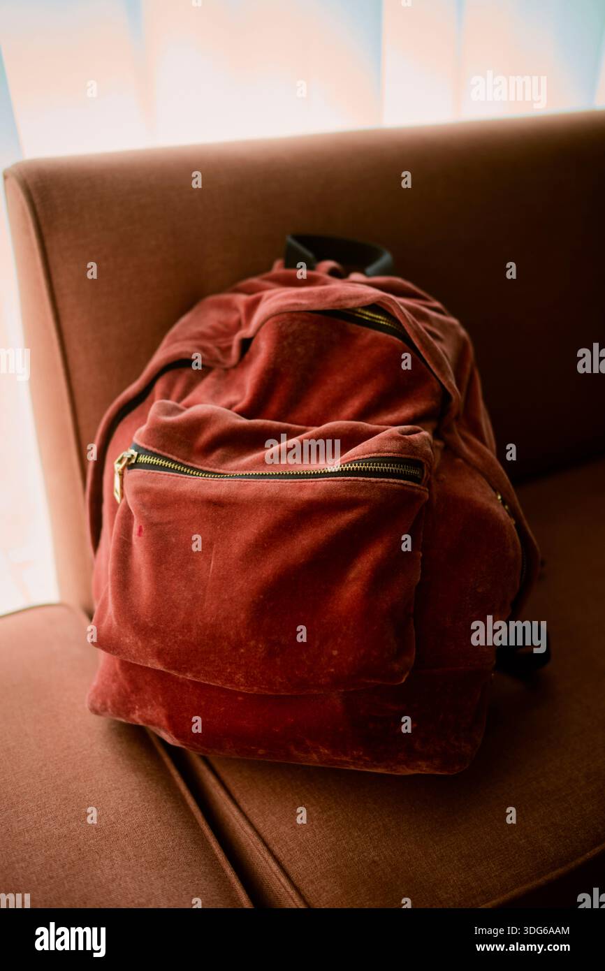 Soft red backpack on a brown sofa under warm sunlight. Chengdu, Sichuan ...
