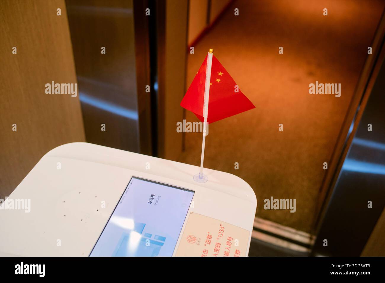 Delivery robot with a small Chinese flag entering an elevator. Chengdu ...