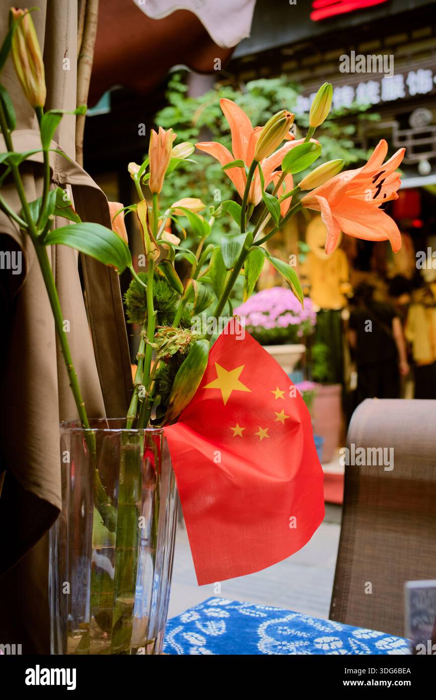 Orange lilies in a vase with a Chinese flag, outdoor market scene in ...
