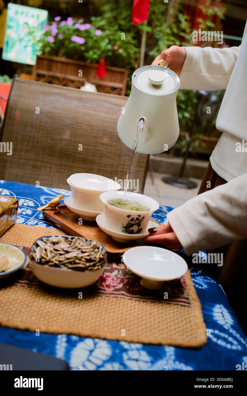 Person pours tea into bowls on a table with snacks and colorful cloth ...