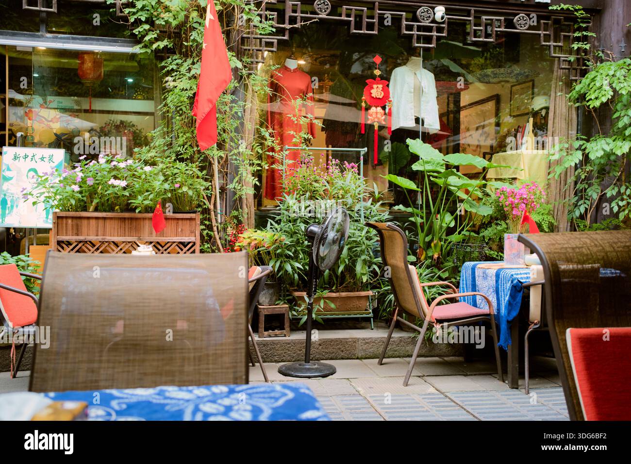 Outdoor cafÈ seating with lush plants, colorful tablecloths, and a fan ...
