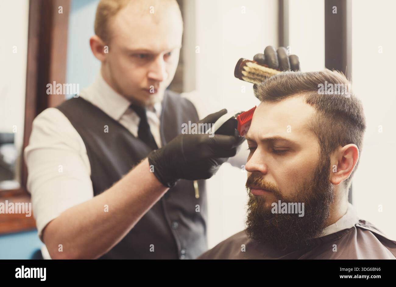 Man getting haircut by hairstylist at barbershop Stock Photo - Alamy