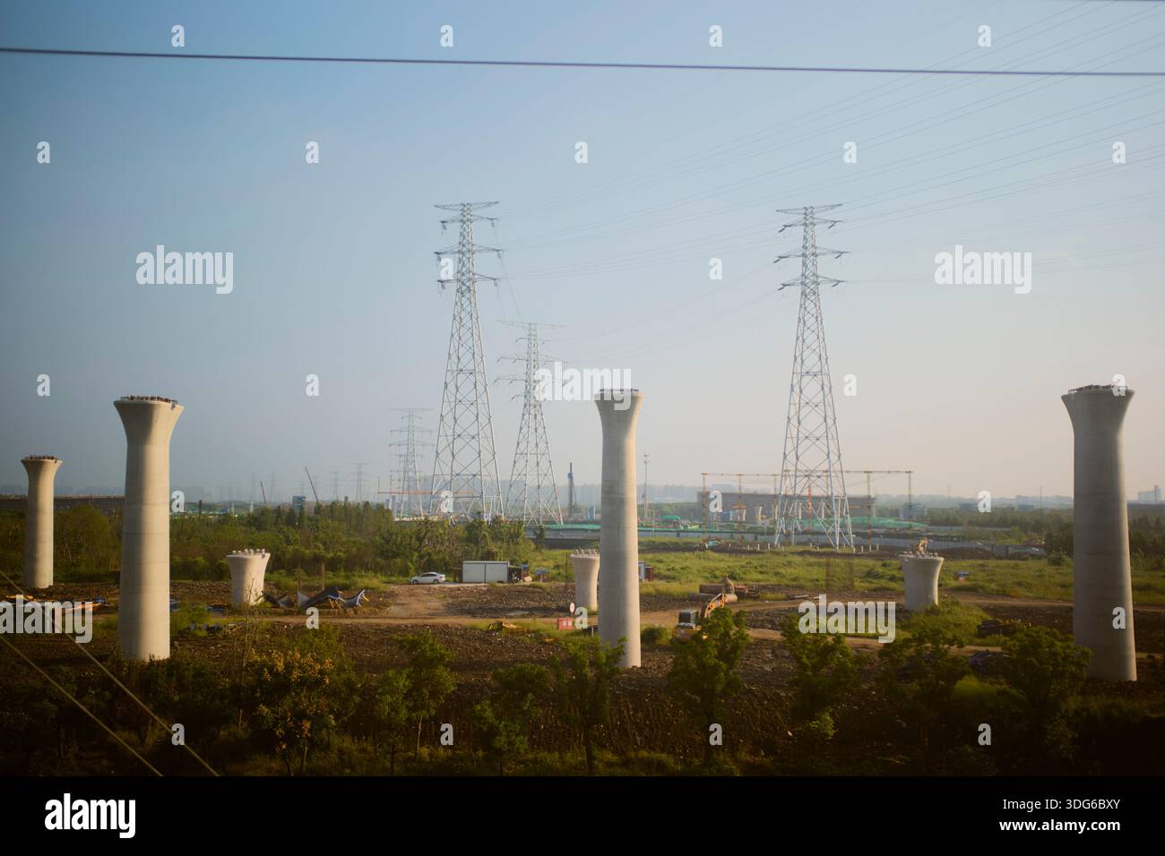 A construction site with large concrete pillars and power lines under a ...