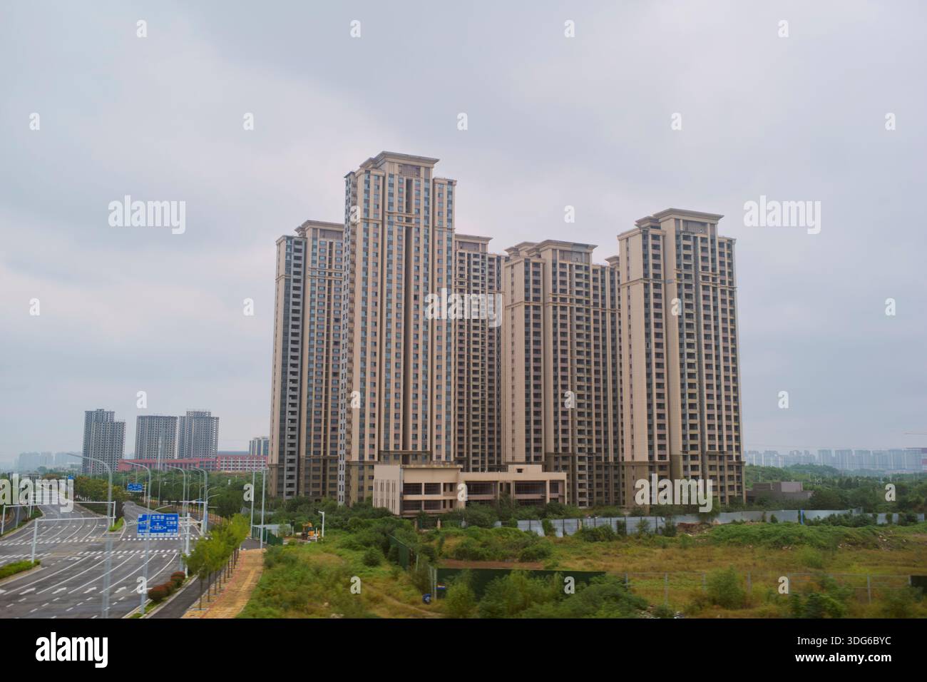 Tall skyscrapers under a cloudy sky with a highway and greenery in the ...
