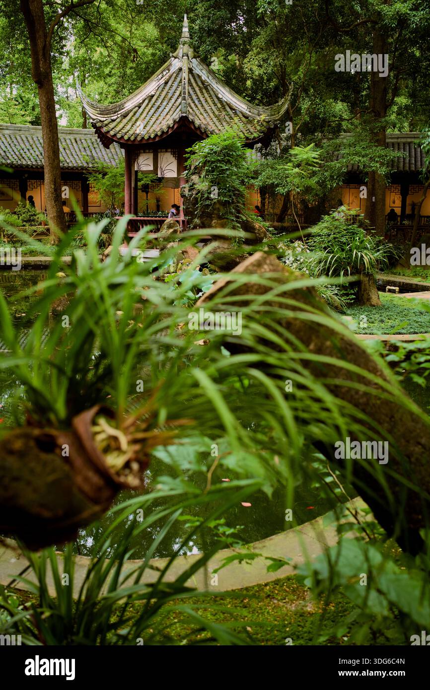 Traditional pagoda surrounded by lush greenery and a serene pond in a ...