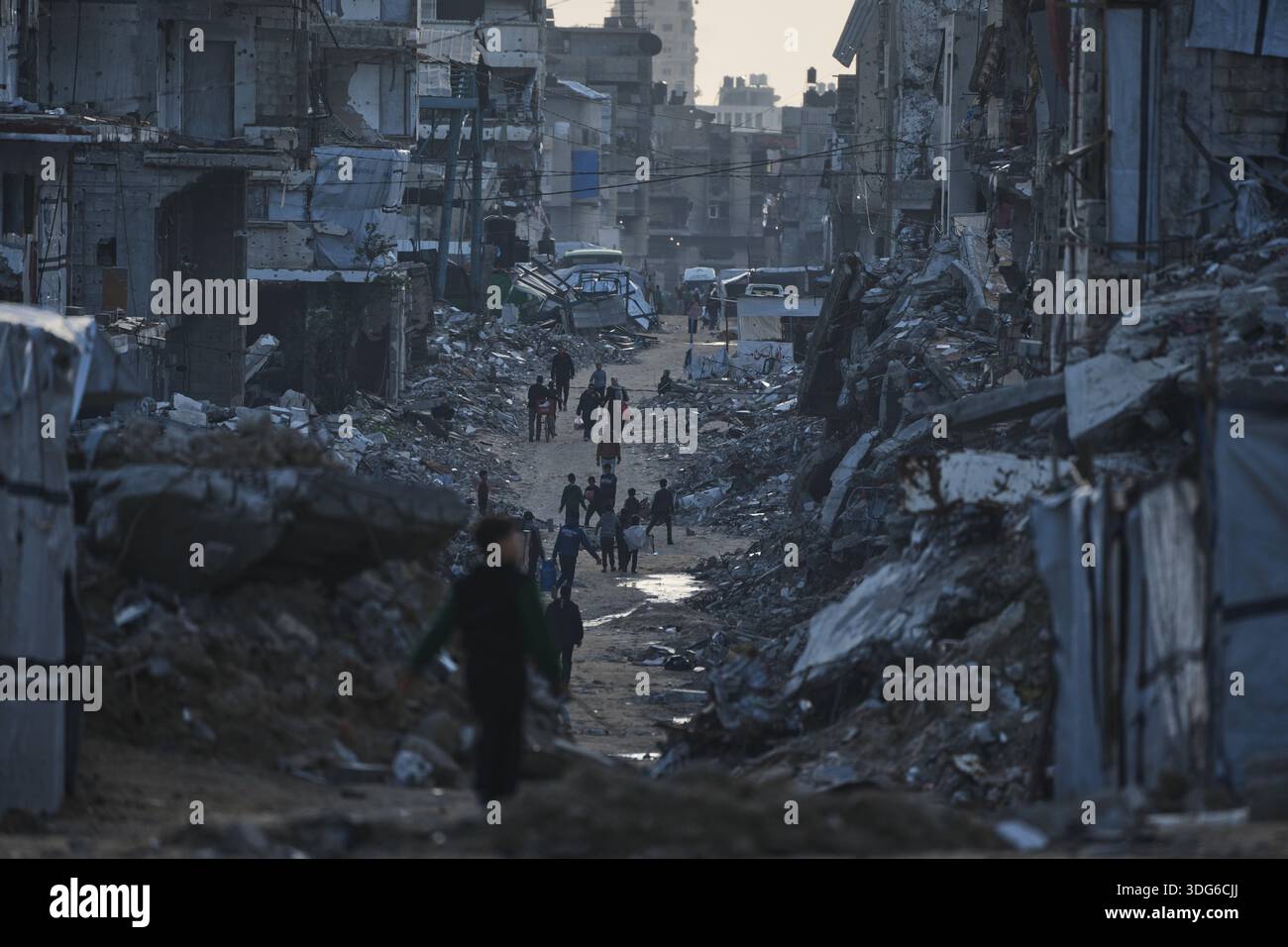 Palestinians walk amid buildings destroyed by Israeli air and ground ...