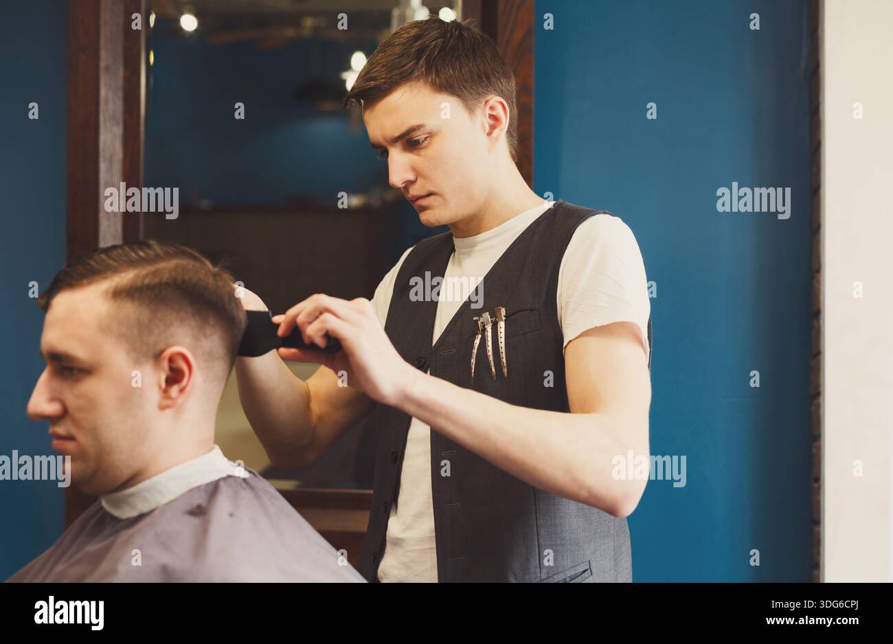 Man getting haircut by hairstylist at barbershop Stock Photo - Alamy