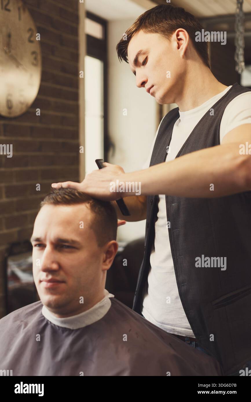 Man getting haircut by hairstylist at barbershop Stock Photo - Alamy