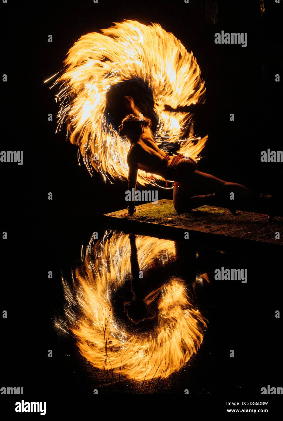 A person performs fire dancing with flames creating a fiery spiral ...
