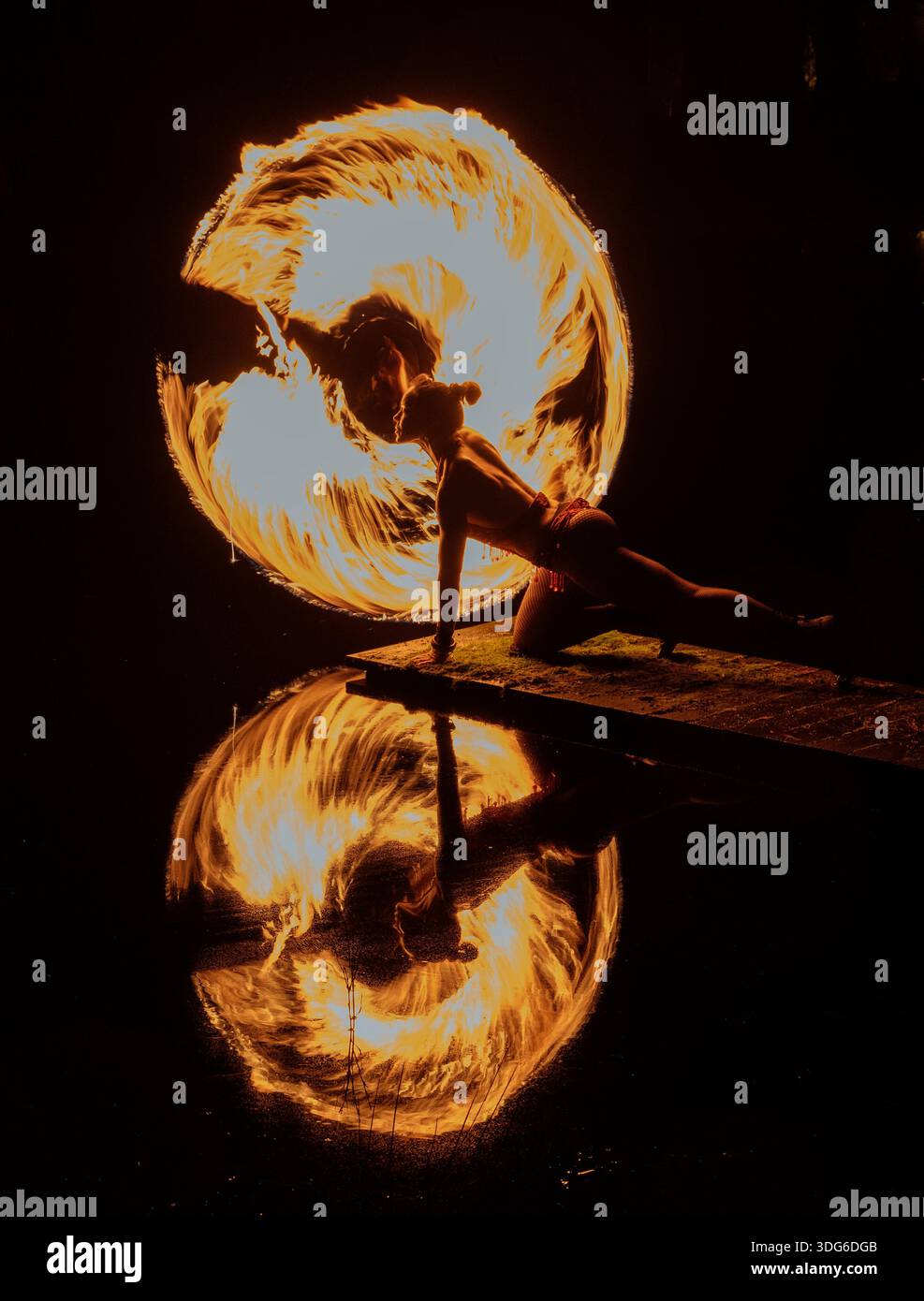 Performer creates mesmerizing fire circle display with fiery reflection ...