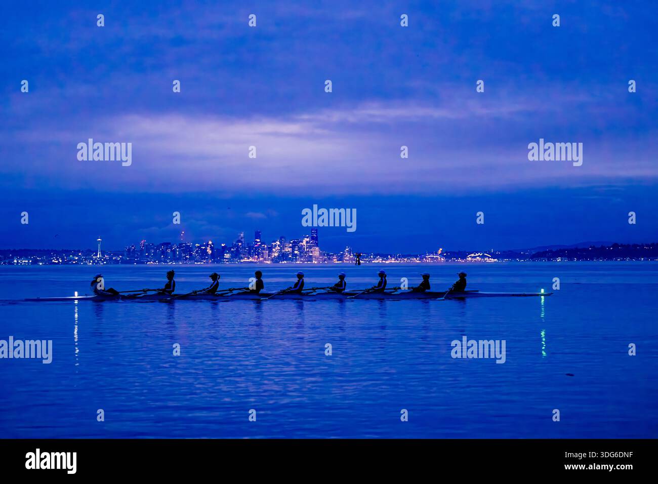 Rowing team glides across calm water at dusk with city skyline in ...