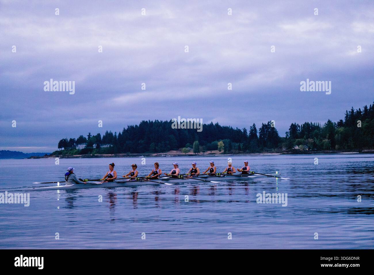 Rowing team glides through calm waters under cloudy skies with a ...
