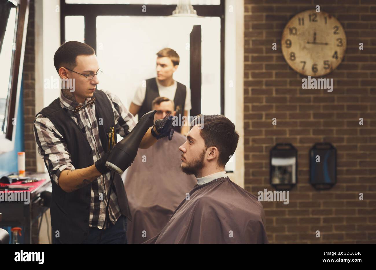 Man getting haircut by hairstylist at barbershop Stock Photo - Alamy