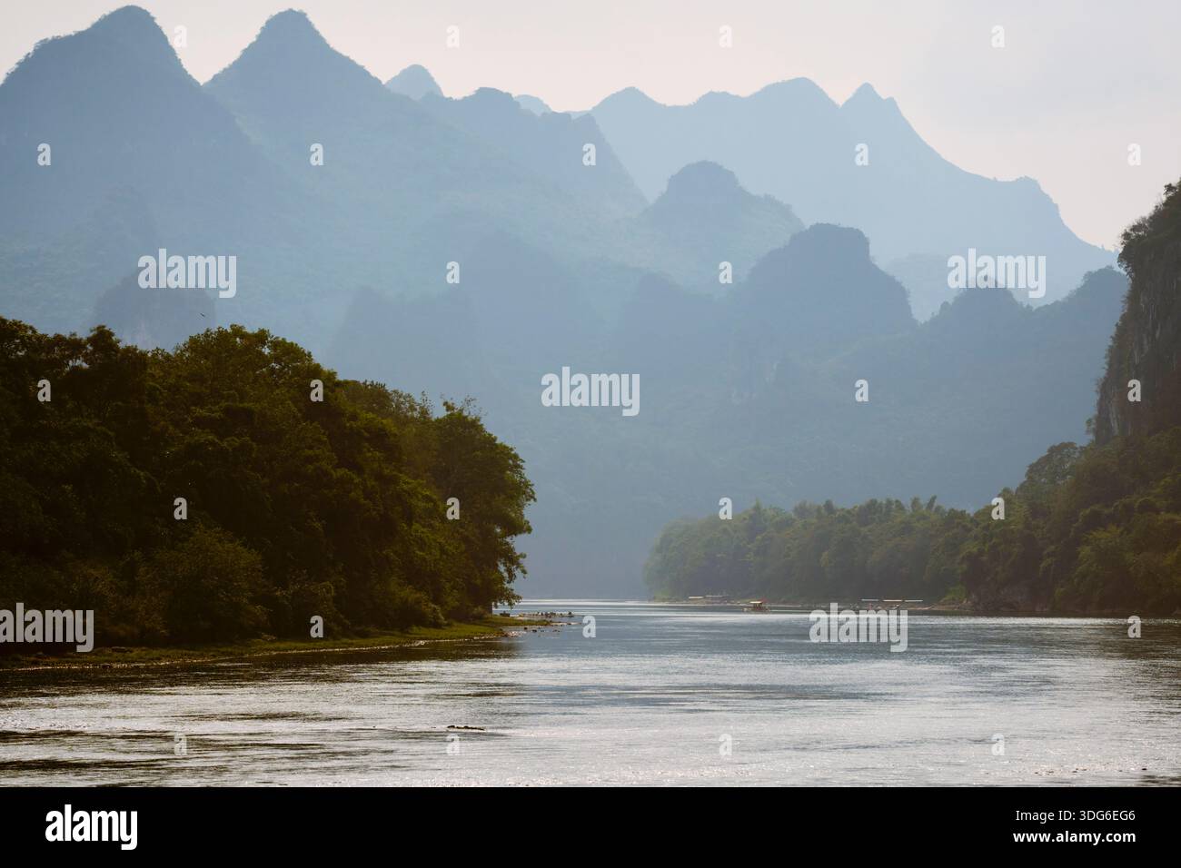 Serene river scene framed by lush trees and distant mountain ...