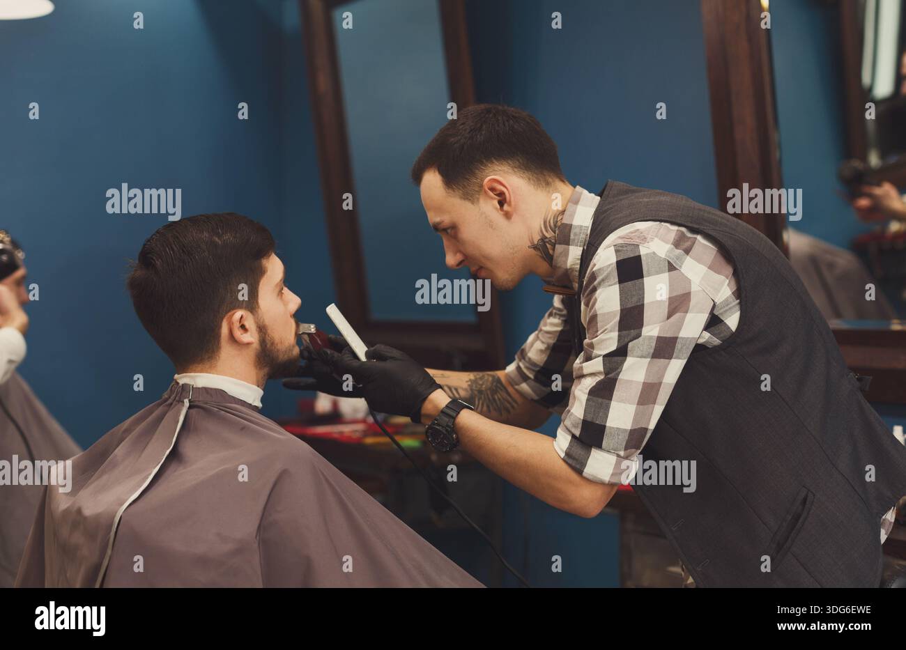 Barber styling beard with trimmer to client at barbershop Stock Photo ...