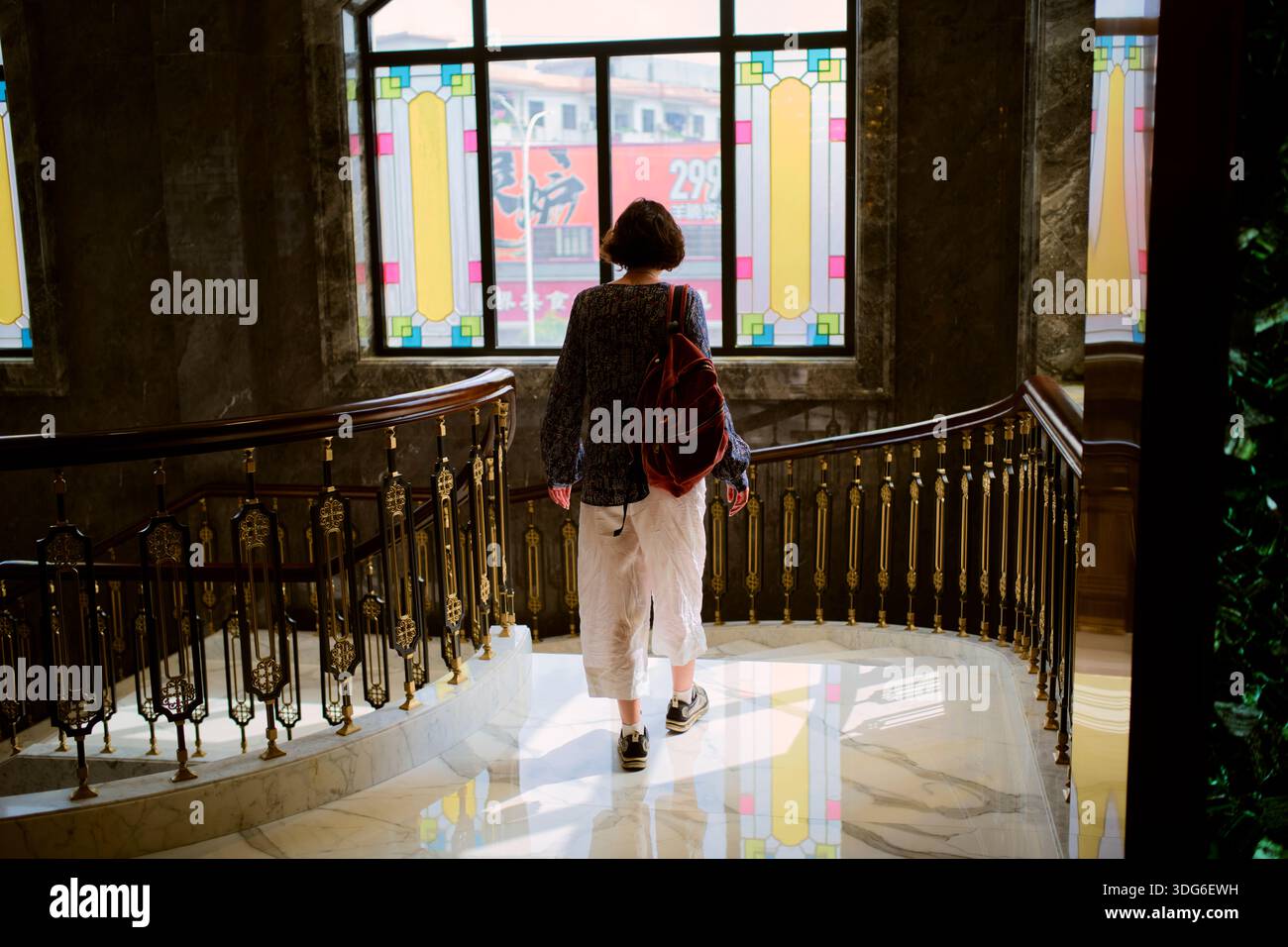 Woman walks up grand marble staircase in an elegant building with ...