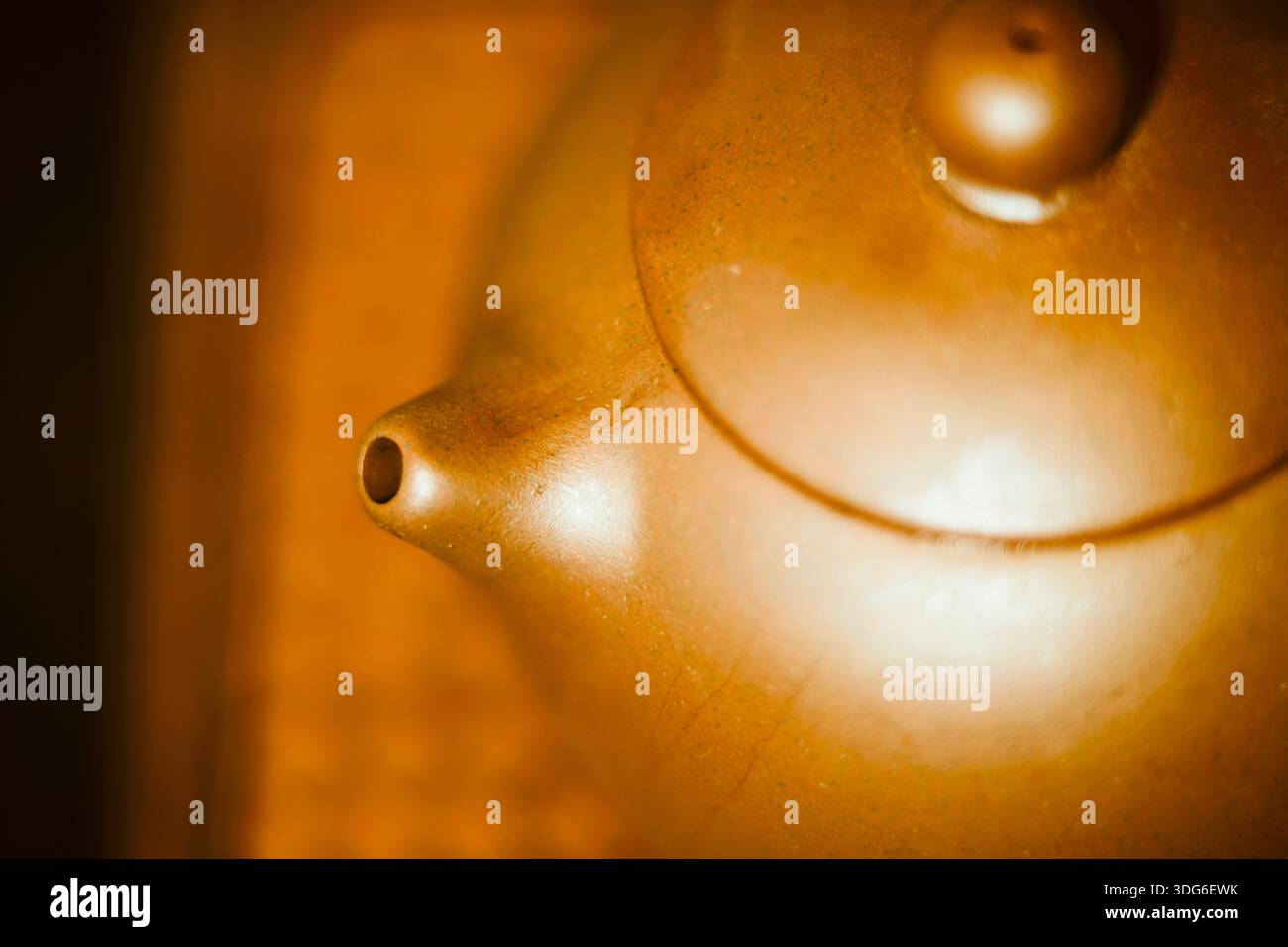 Close-up of a smooth brown teapot spout and lid on a wooden surface ...