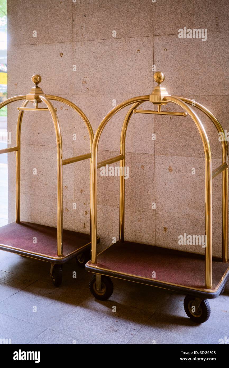 Two brass luggage trolleys on a gray stone floor in a hotel lobby ...