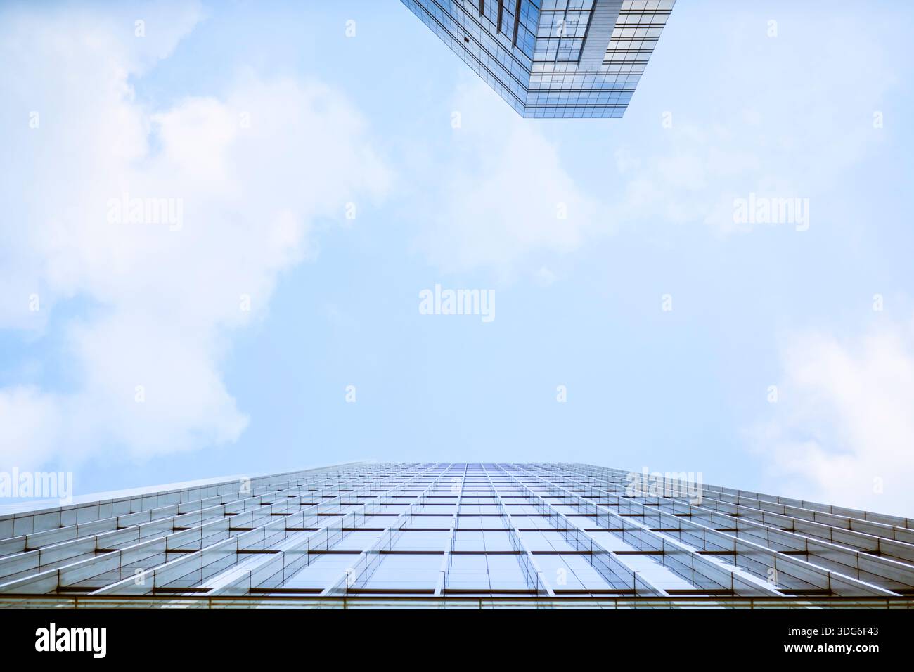 Upward view of two modern skyscrapers against a blue sky with clouds ...