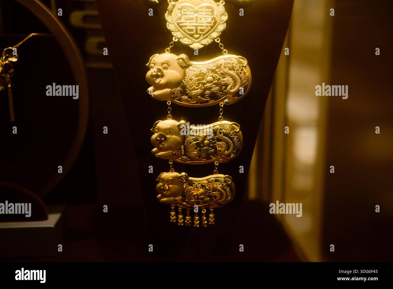 Golden ornate charms with pig designs hang elegantly on a dark display ...