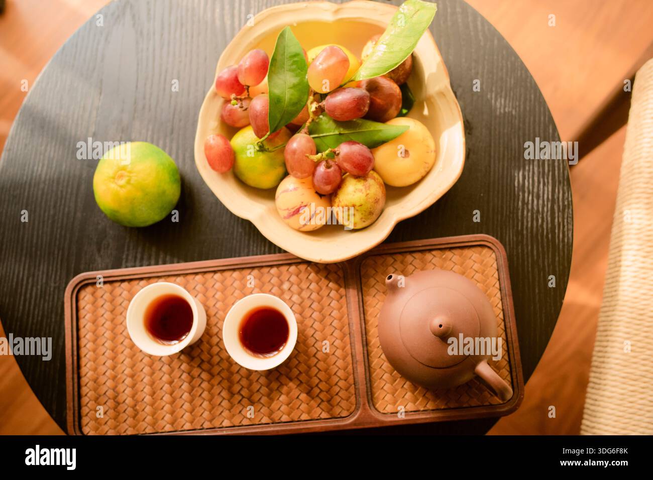A wooden table with fruit, a teapot, and two cups of tea arranged ...