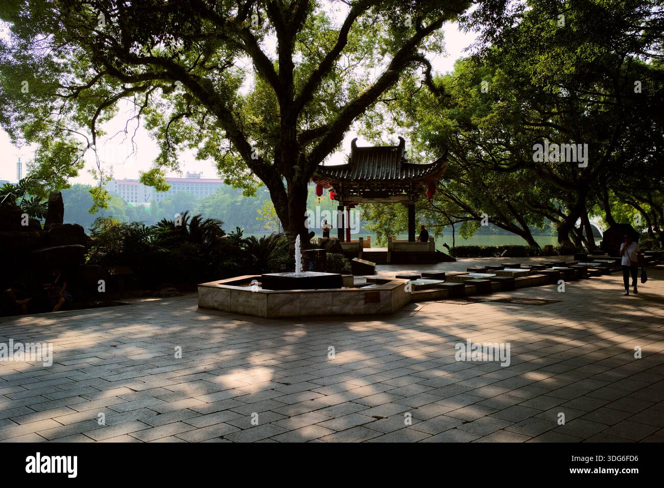 Tranquil park scene with a pagoda, trees, and a small water feature ...