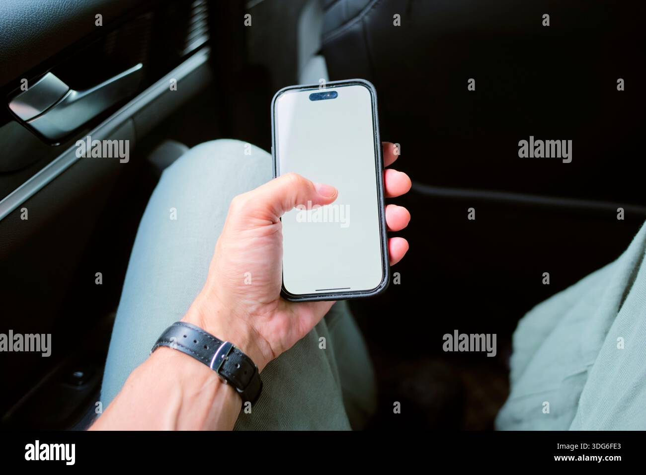 Hand holding a smartphone with a blank screen inside a car. Trip from ...