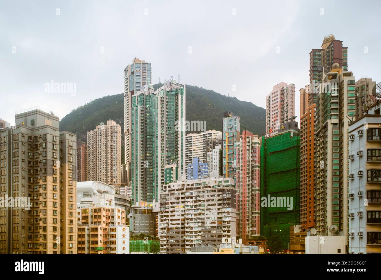 Skyscrapers rise against a lush mountain backdrop in a bustling ...