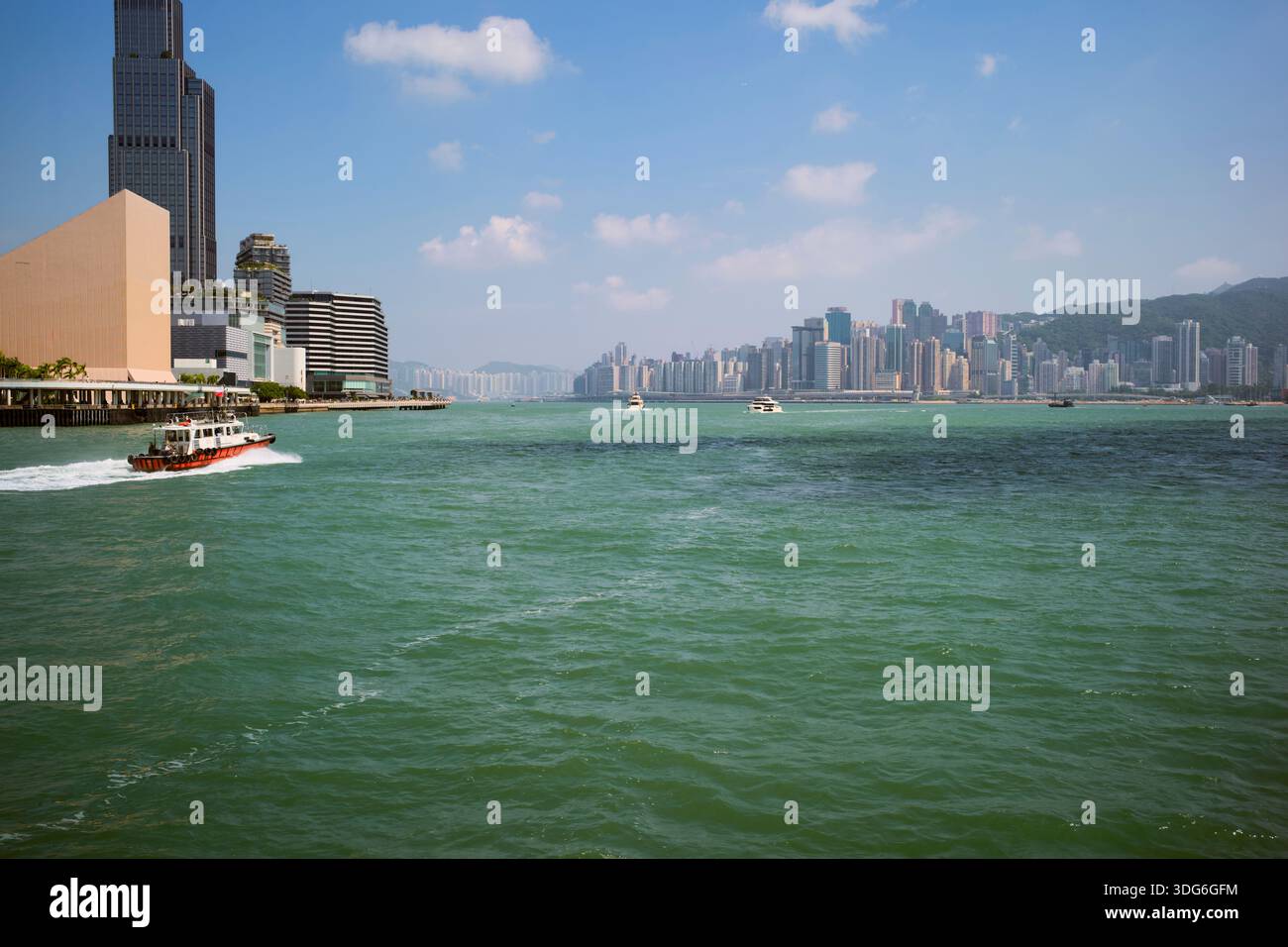 Boats cruise through vibrant blue-green water with a city skyline under ...