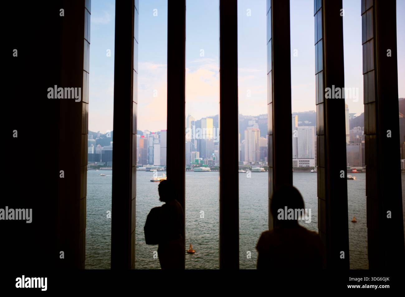 Silhouettes standing by tall windows overlooking a city skyline and ...