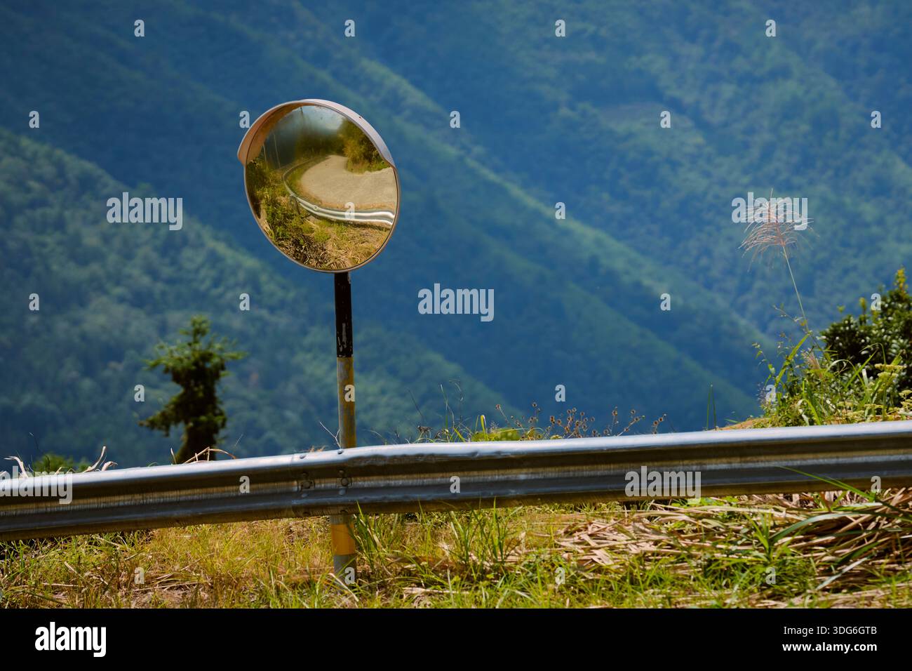 Curved mirror reflects road landscape on a mountain side under a clear ...