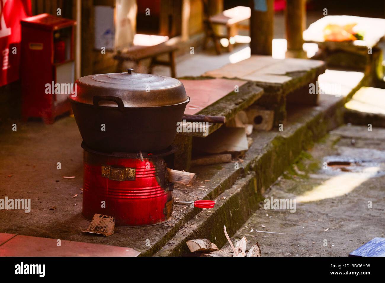 Large black pot on a traditional outdoor clay stove in a rustic setting ...