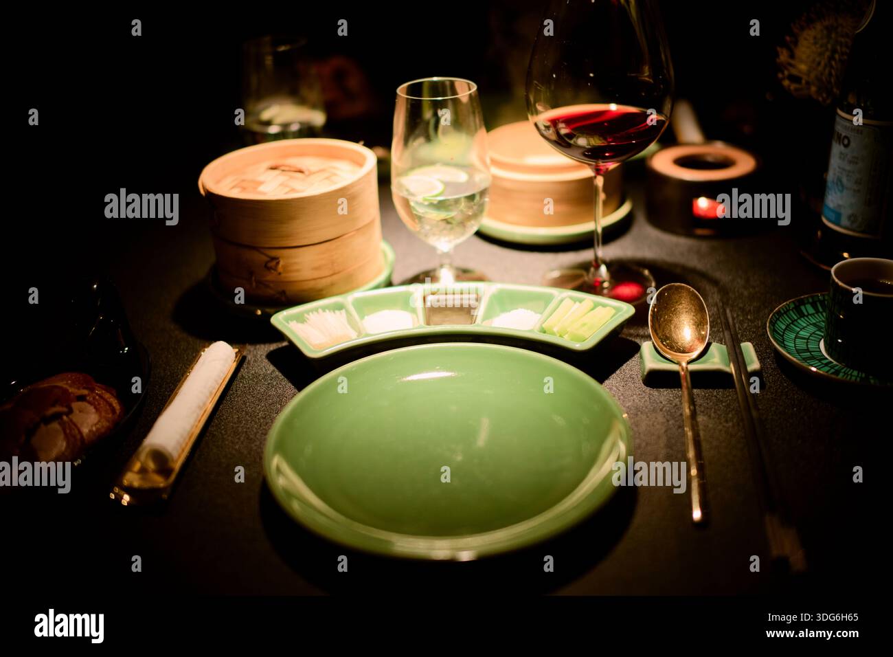Empty green plate and glassware on a dimly lit dining table with ...