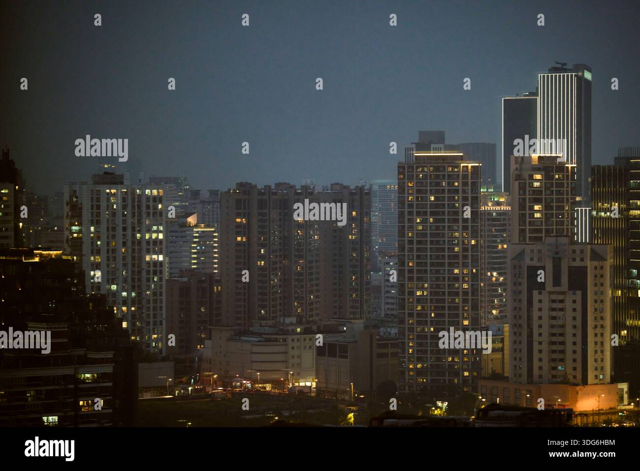 City skyline at night with tall buildings lit by windows against a dark ...