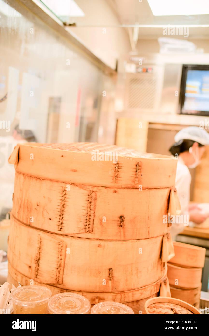 Large bamboo steamers stacked in a kitchen with a chef working in the ...