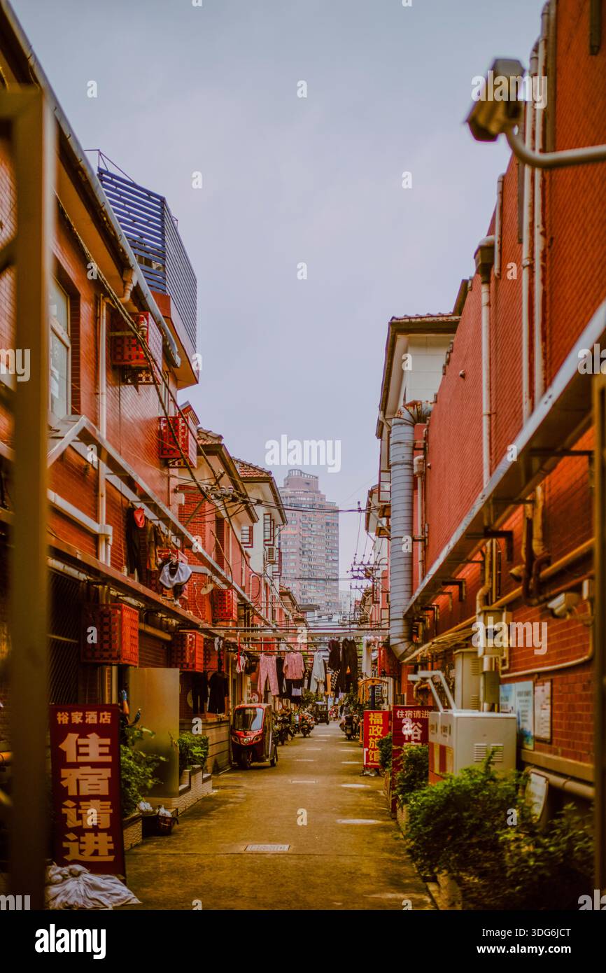 Narrow urban alleyway with brick buildings, signs, and a distant city ...