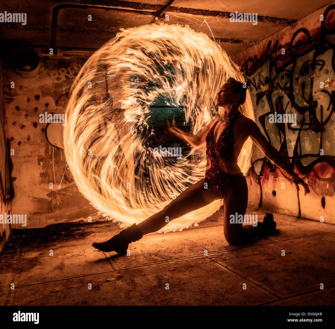 Woman performing fire spinning in a graffiti-covered urban setting. WA ...