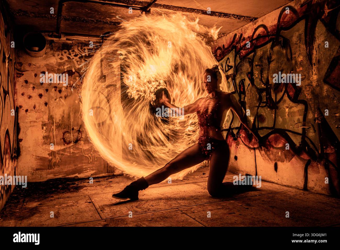 Woman performing fire spinning in a graffiti-covered urban setting. WA ...