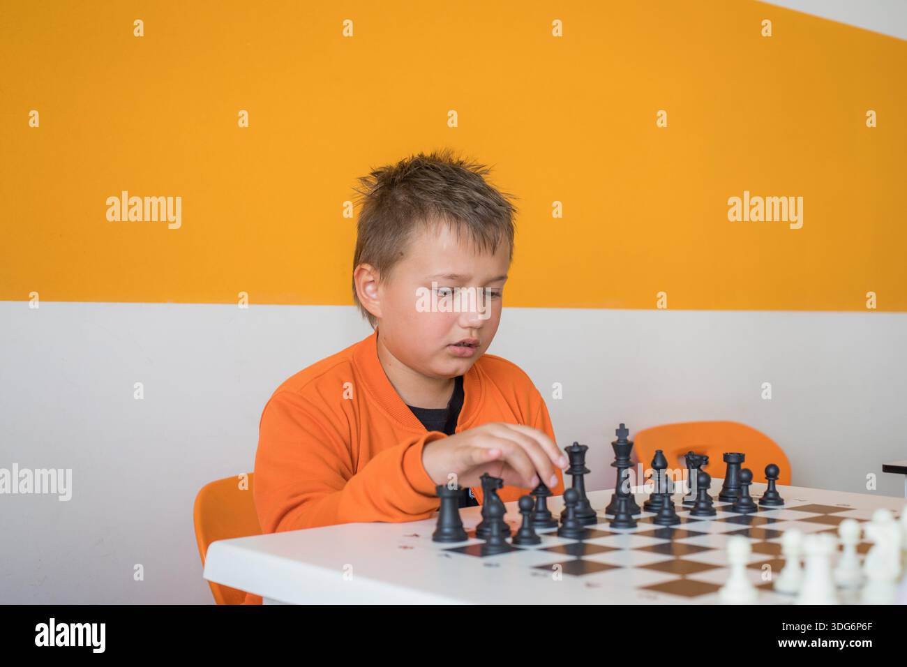 Serious school boy student playing chess in the classroom. Child with ...