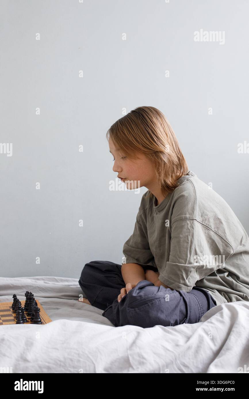 Clever child boy playing chess board game indoor. Kid 11 years old with ...