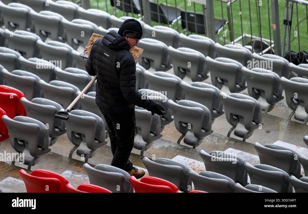 Employee sprinkling sand on the stairs and ramps, Allianz Arena Munich ...