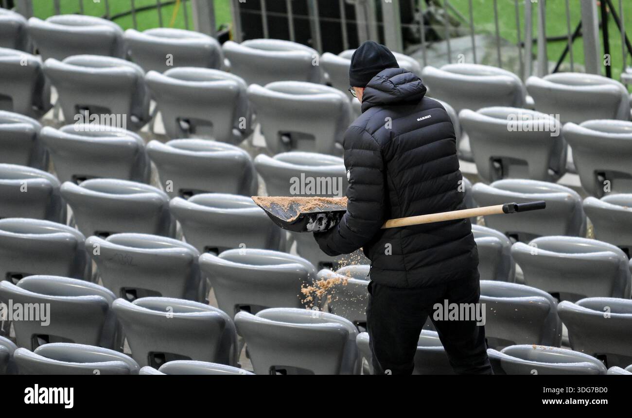 Employee sprinkling sand on the stairs and ramps, Allianz Arena Munich ...